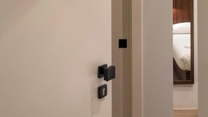Quarto de hotel com porta identificada como '101', cama com roupa de cama branca e design moderno na parede.