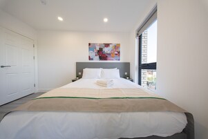 Quarto de hotel com uma cama, um quadro na parede e uma janela.
