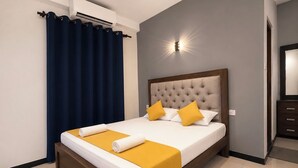 Quarto de hotel com cama, mesa de cabeceira, espelho e aparelho de ar condicionado.