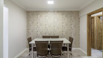 Uma sala de jantar com uma mesa e cadeiras, papel de parede floral e uma porta de madeira.