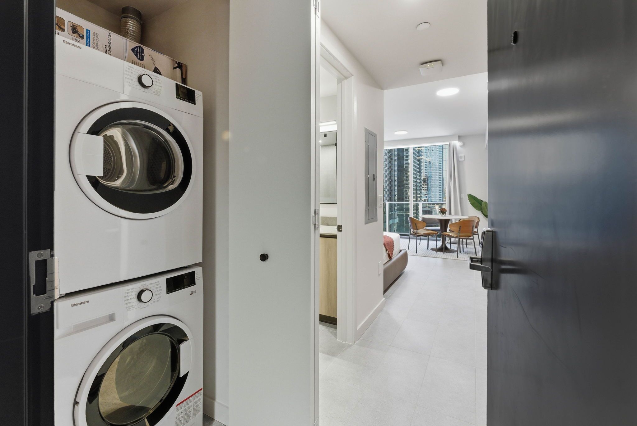 Um apartamento moderno com área de lavanderia, espaço de refeições com vista e uma janela grande.