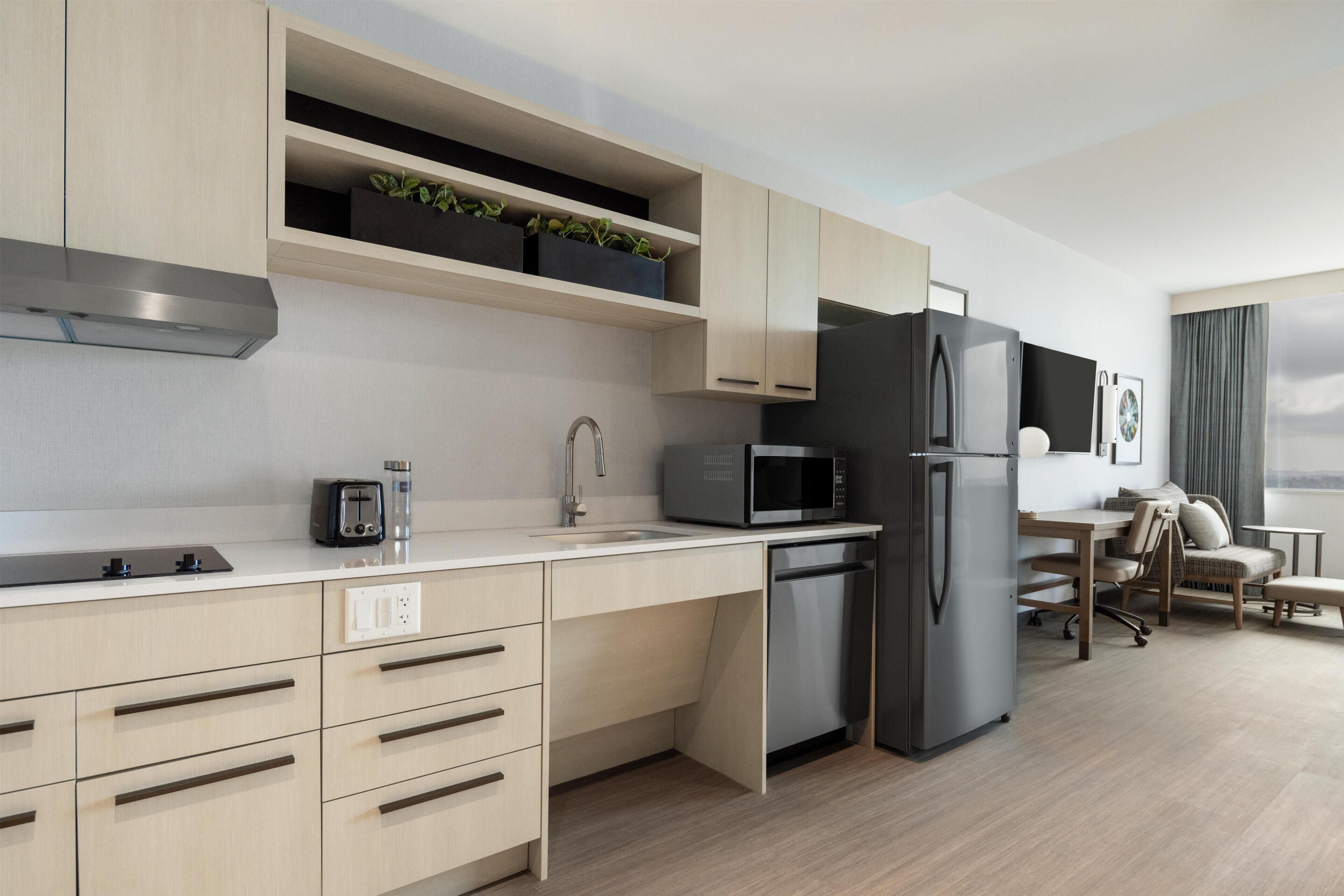 Cozinha moderna com eletrodomésticos embutidos, sala de jantar com mesa e cadeiras, e vista para a cidade.