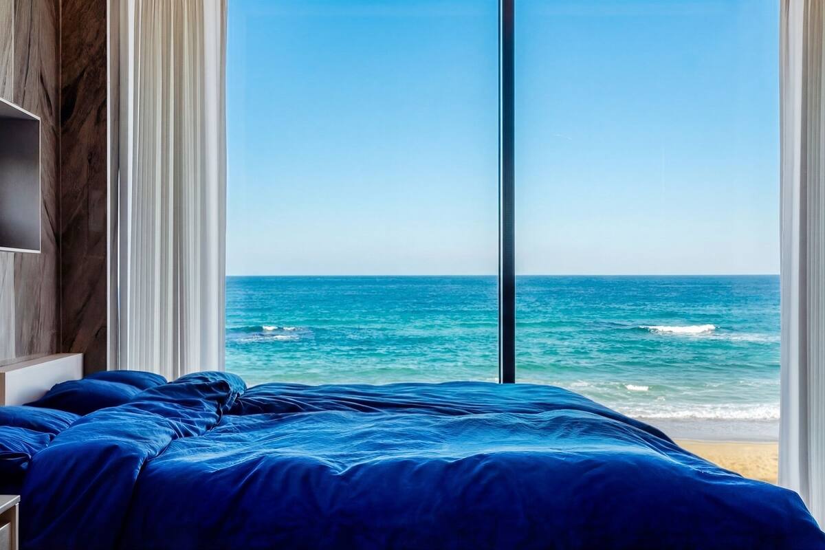 Quarto com uma grande janela com vista para o oceano.
