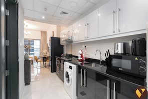 Uma cozinha moderna com eletrodomésticos de aço inoxidável, uma máquina de lavar e um espaço de refeições com vista.