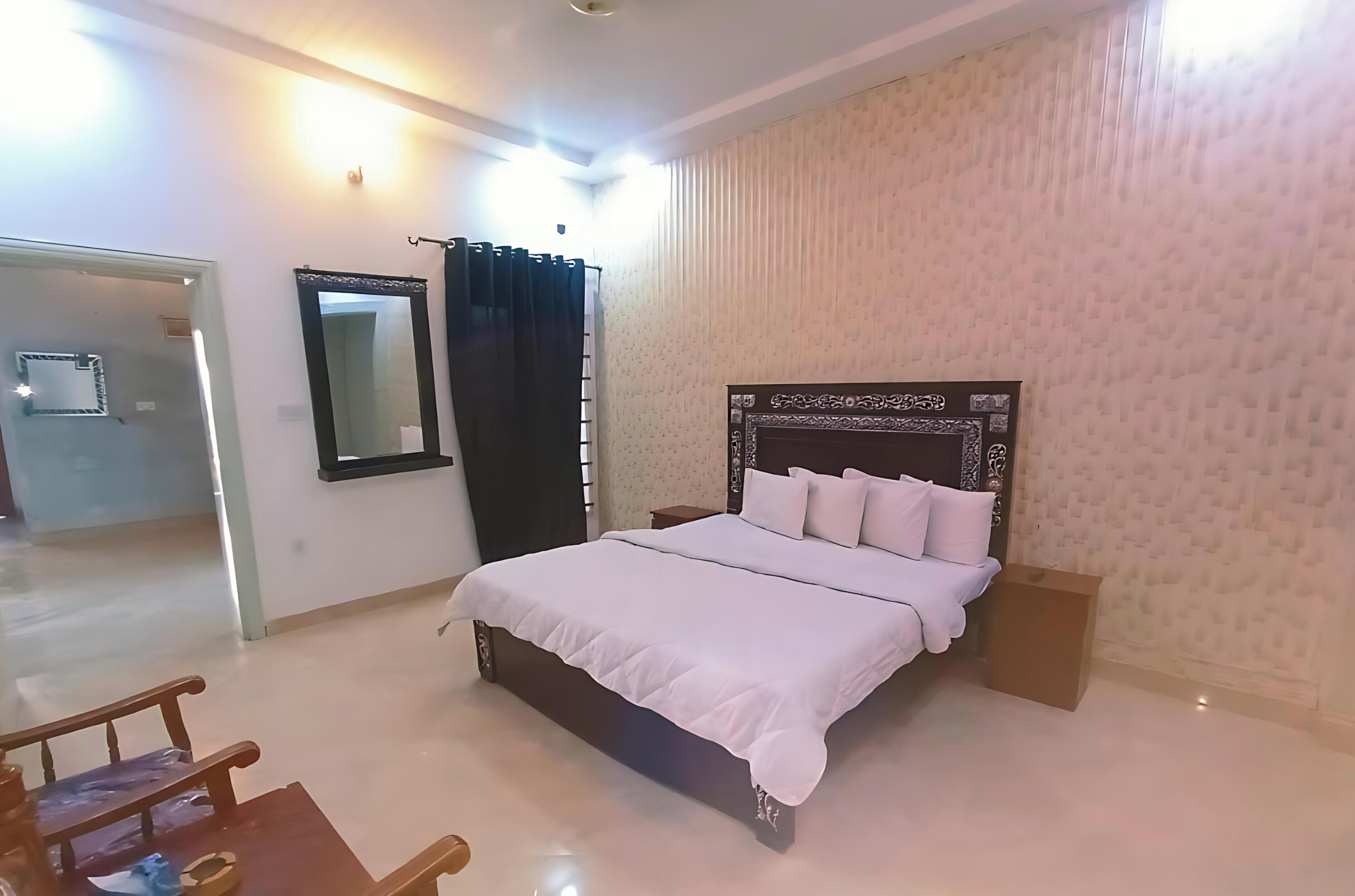 Quarto com uma cama grande, mesa de cabeceira, espelho e guarda-roupa.