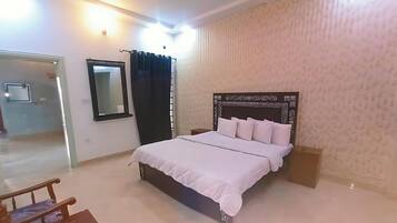 Quarto com uma cama grande, mesa de cabeceira, espelho e guarda-roupa.