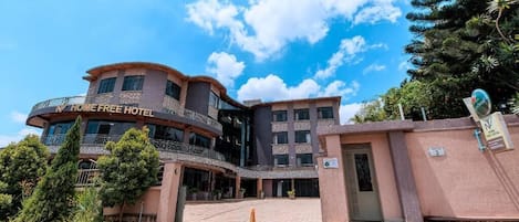 Um hotel com vários andares, fachada curva, varanda e uma placa com a inscrição "HOME FREE HOTEL".