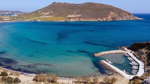 Uma área costeira com mar azul cristalino, uma praia arenosa e uma península rochosa.