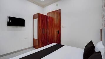 Quarto com cama, guarda-roupa, televisão de tela plana e luminária no teto.
