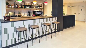 Uma área de bar com balcão, banquetes e diversos tipos de garrafas e copos.