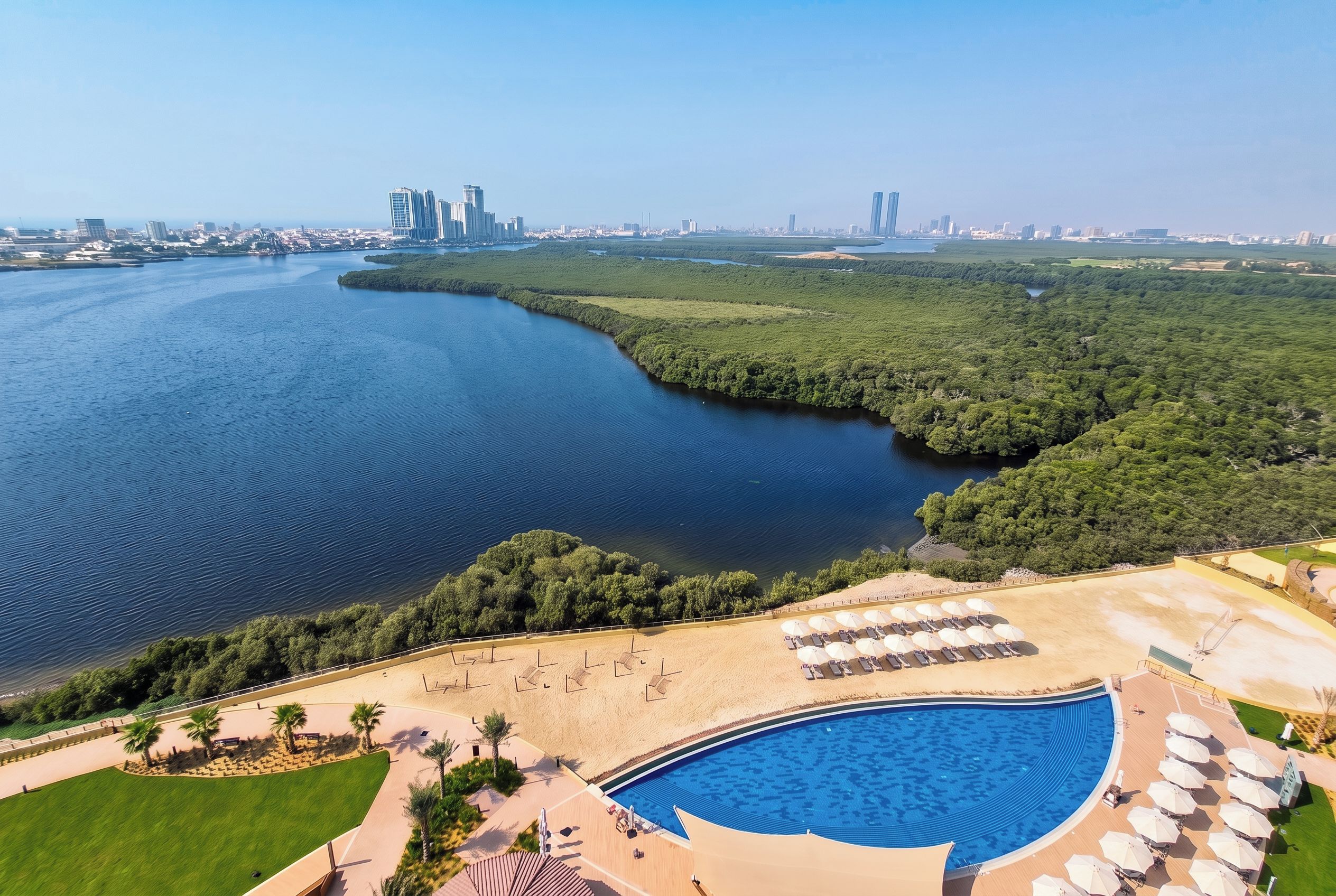 Um resort com piscina, área de praia e vista para o rio e o horizonte da cidade.
