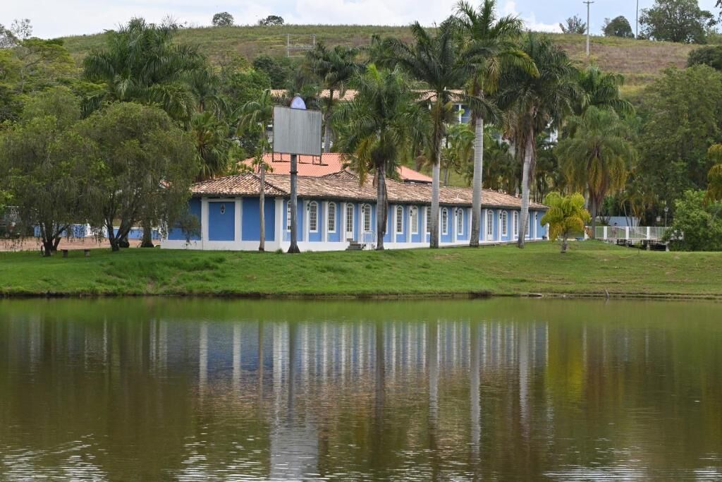 Um edifício com fachada azul e telhado telhado, cercado por palmeiras e um corpo d'água.