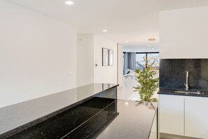 Uma cozinha moderna com bancada preta, armários brancos e painel de fundo preto.