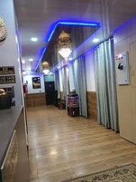 Um hall de hotel com piso de madeira, balcão de recepção, aquário e um candelabro.