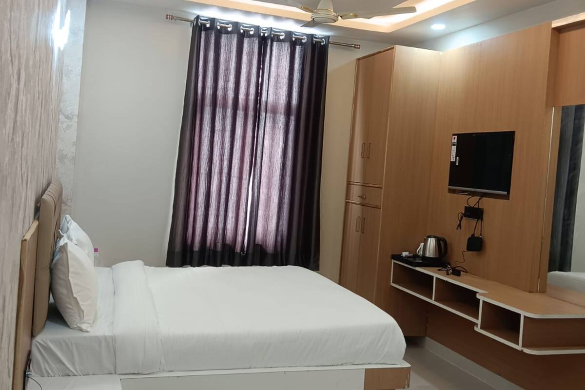 Quarto moderno com cama, TV, ventoinha no teto e guarda-roupa de madeira.