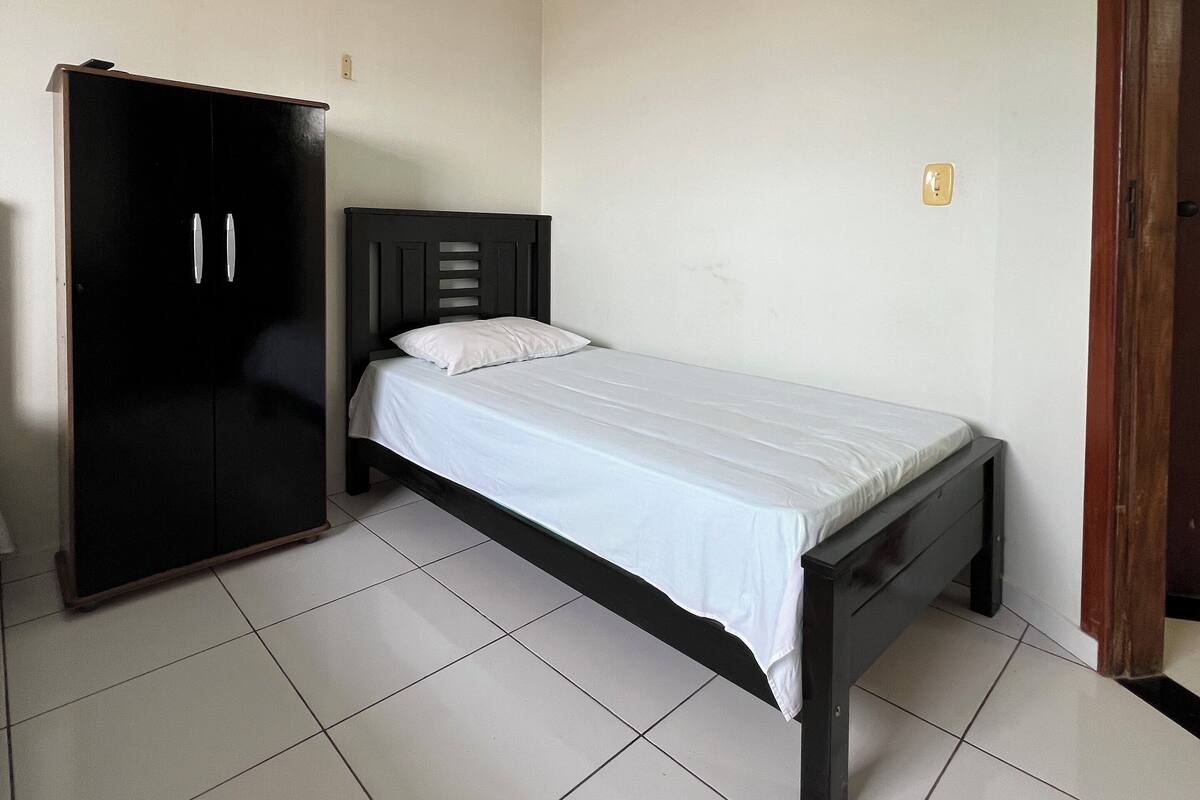 Um quarto com cama, guarda-roupa e ar condicionado.