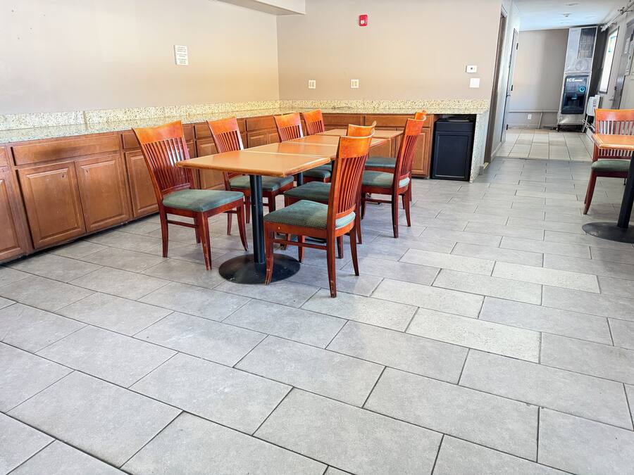 Uma área de refeições com uma mesa comprida e cadeiras, um balcão de cozinha e piso ladrilhado.