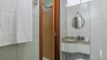 Casa de banho com porta de madeira, pia com espelho e sanita.
