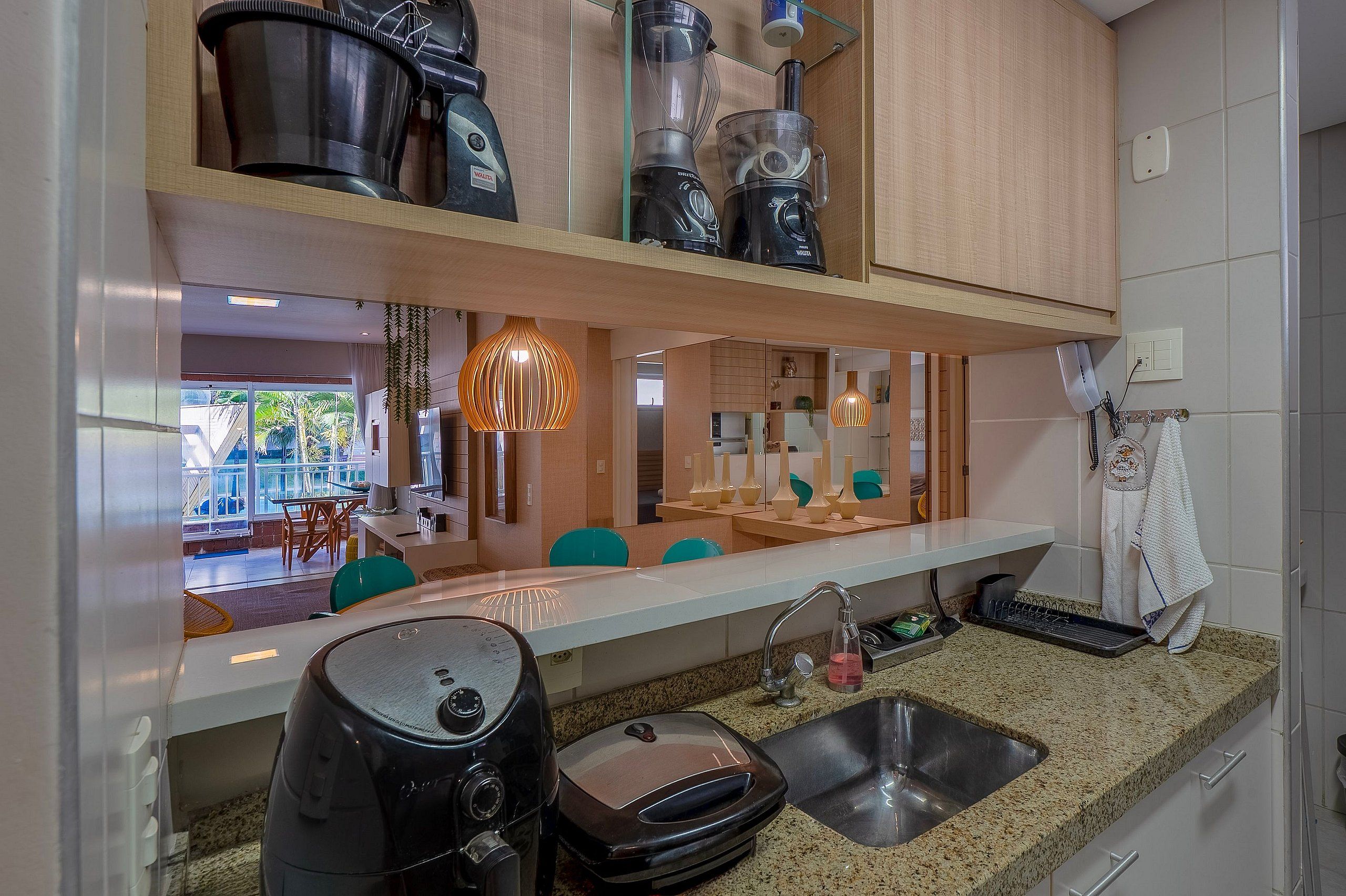 Cozinha moderna com bancada de granito, cafeteira, chaleira e liquidificador na prateleira.