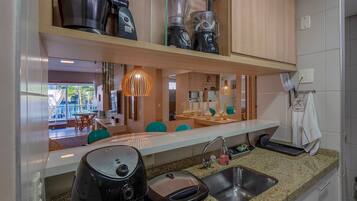 Cozinha moderna com bancada de granito, cafeteira, chaleira e liquidificador na prateleira.