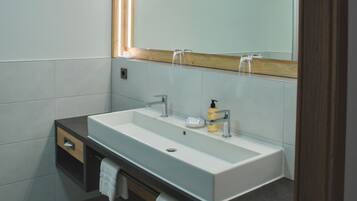 Uma casa de banho moderna com um espelho grande, uma pia branca e um porta-toalhas.