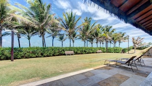 Uma área externa pavimentada com palmeiras, bancos e cadeiras de lounge.
