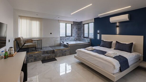 Quarto moderno com uma cama grande, uma escrivaninha, um espaço de estar e uma banheira.