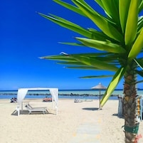 Praia particular, areia branca, guarda-sóis, toalhas de praia 