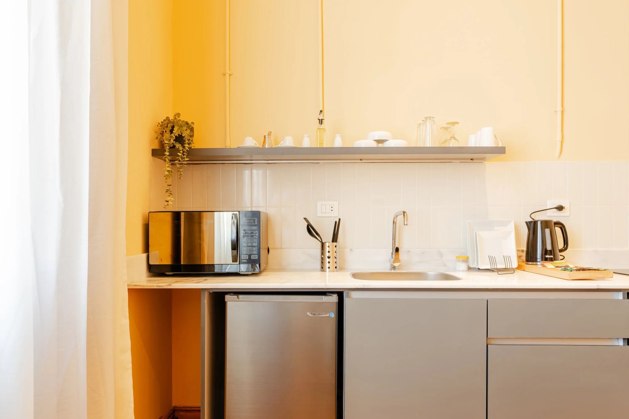 Uma cozinha compacta com micro-ondas, pia e cafeteira.