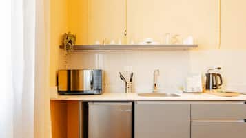 Uma cozinha compacta com micro-ondas, pia e cafeteira.