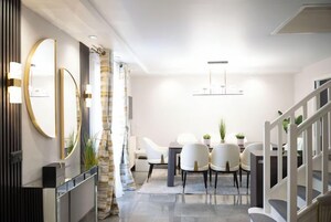 Uma sala de jantar moderna com mesa branca, quatro cadeiras e um candelabro.