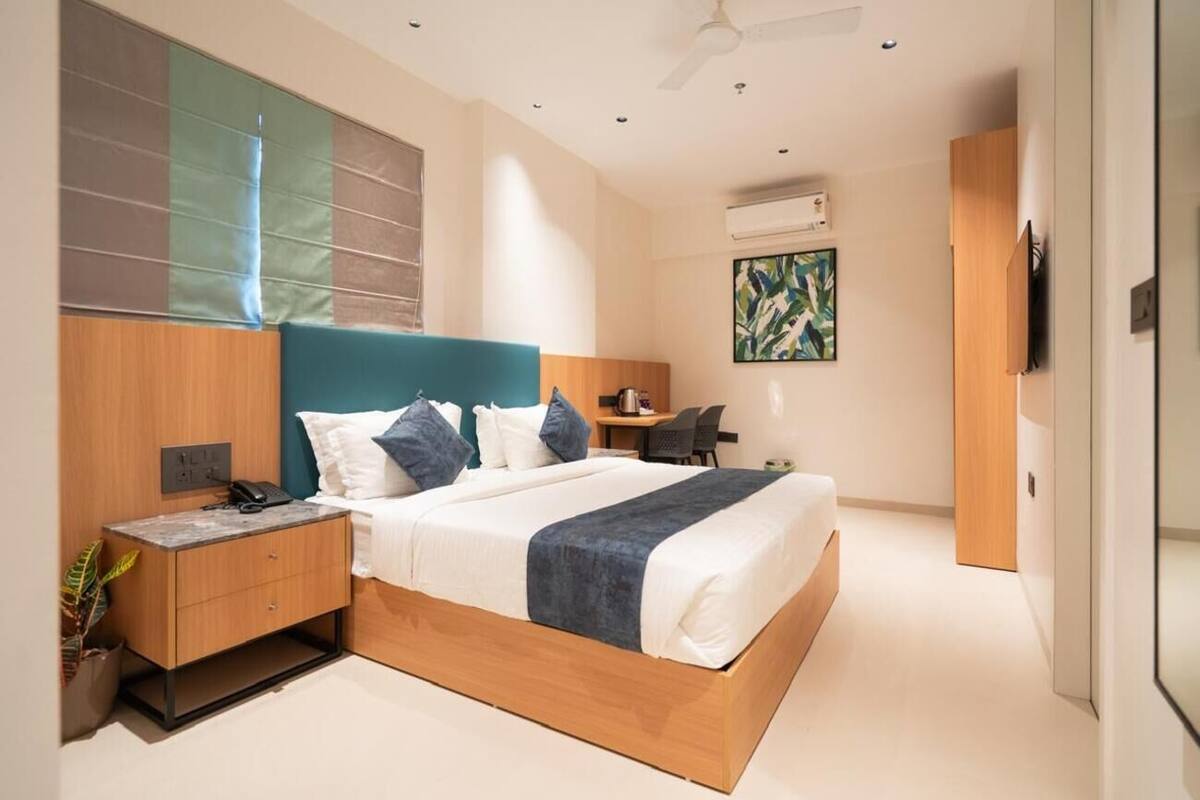 Quarto de hotel moderno com uma cama grande, uma mesa de cabeceira, uma escrivaninha e uma cadeira.