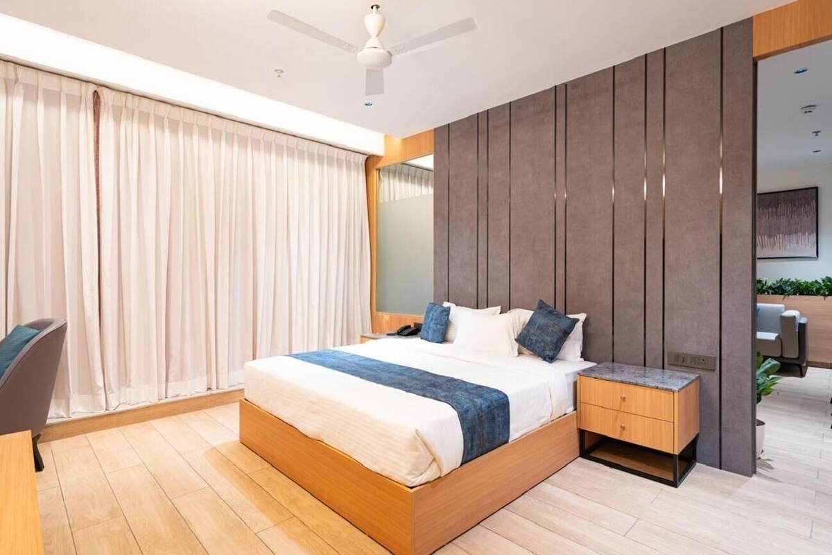 Quarto moderno com uma cama grande, mesa de cabeceira, escrivaninha e cadeira.