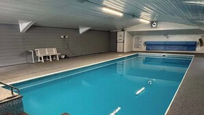 Piscina interna com chão de azulejos, bancos e posto de salva-vidas.
