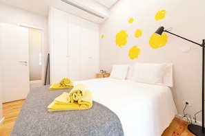 Quarto de hotel com uma cama, uma escrivaninha e um guarda-roupa.