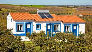 Uma casa branca e azul com telhado vermelho, painéis solares e um reservatório de água.