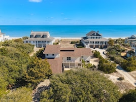 Uma área residencial costeira com várias casas, uma praia e uma vista clara do oceano.