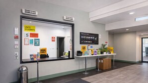 Uma área de recepção com tapete de boas-vindas, um mural de avisos e uma placa com a inscrição 'Conheça sua equipe'.