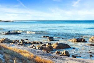 Paisagem costeira com costas rochosas e águas azul-claras.