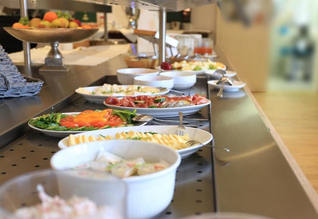 Buffet com diversos pratos, incluindo saladas, carnes e frutas.