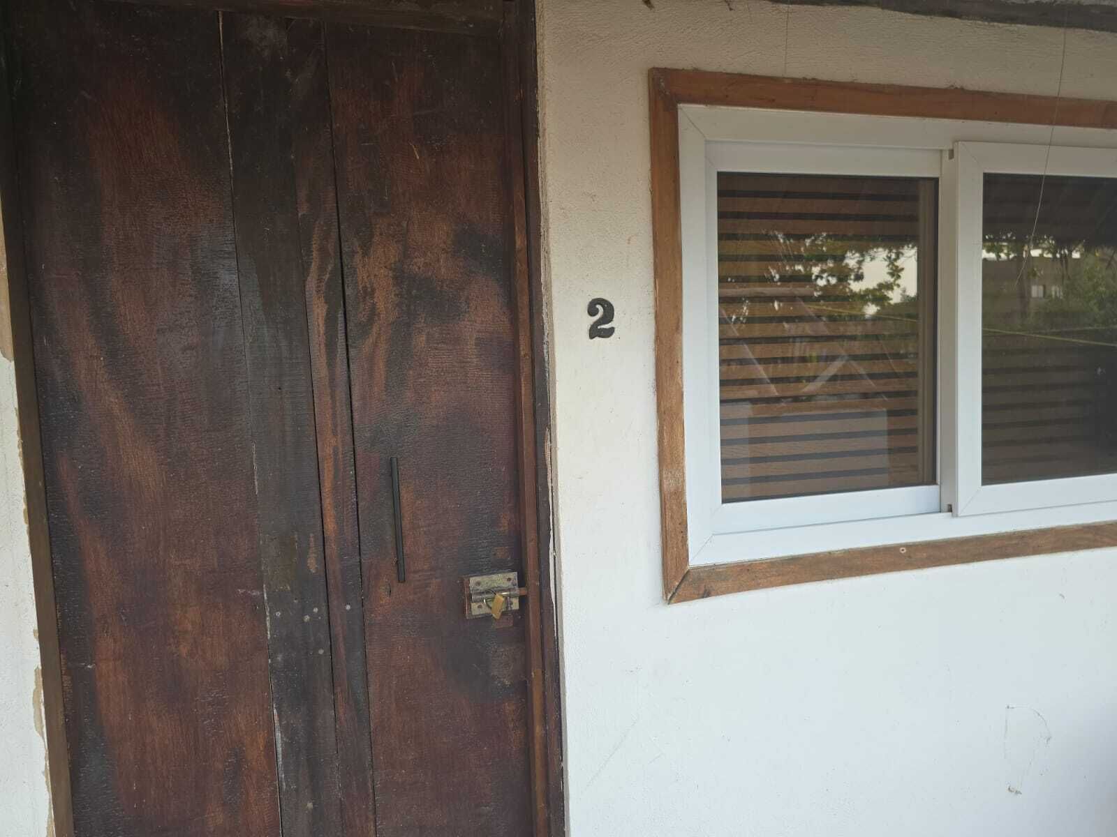 Uma porta de madeira com maçaneta de latão e janela com persianas.