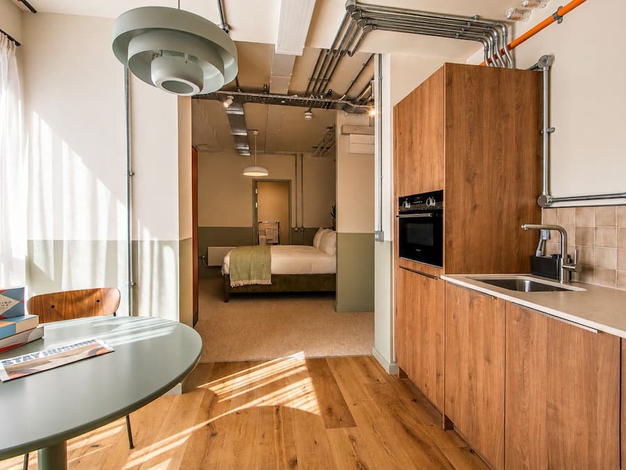 Quarto de hotel compacto com cozinha compacta, uma cama e área de refeições.