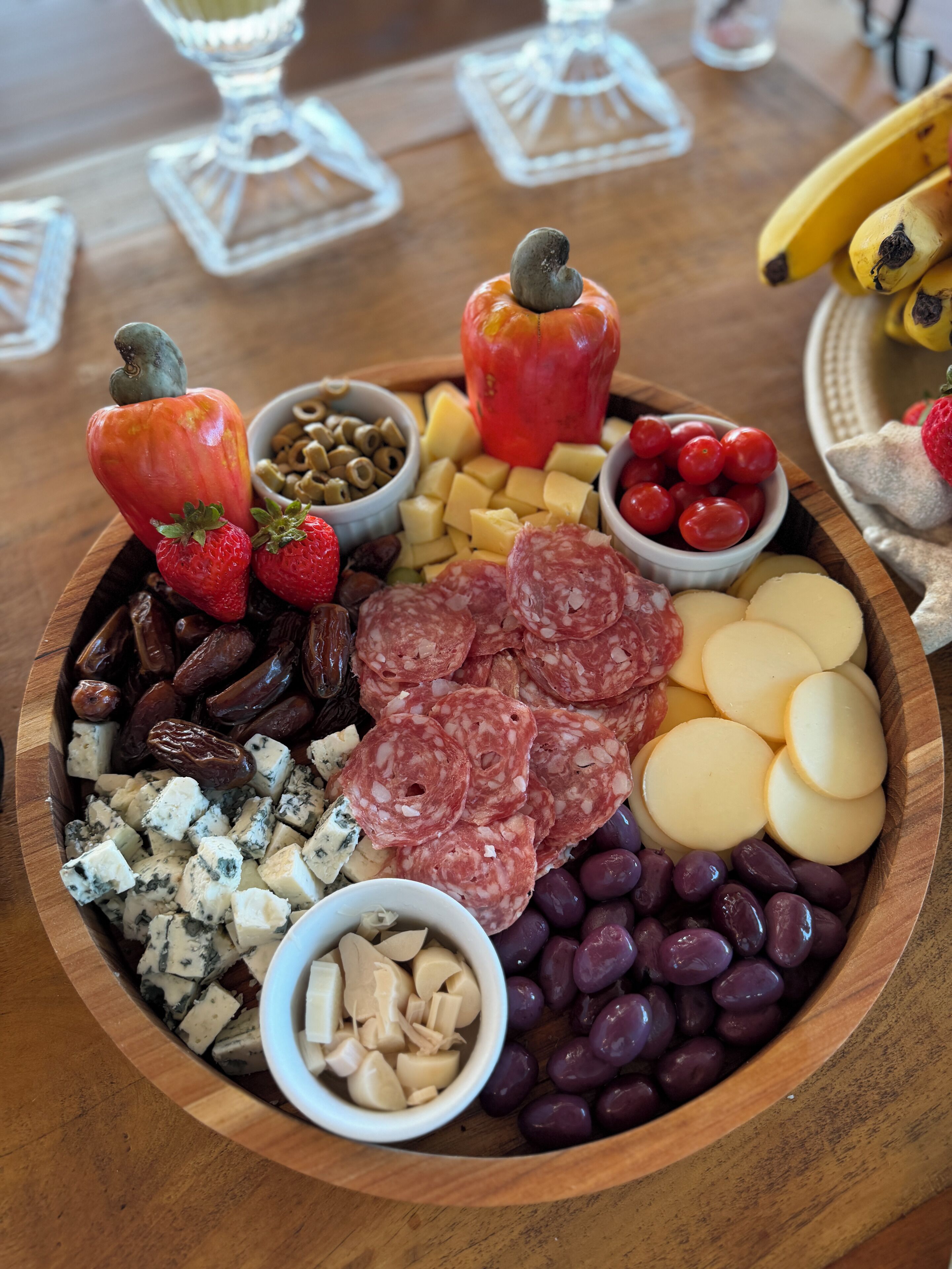 Tábua de madeira com diversos alimentos, incluindo frutas, queijos e carnes.