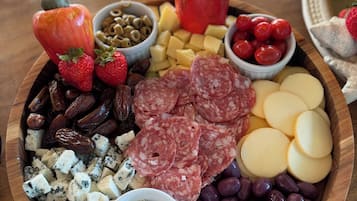 Tábua de madeira com diversos alimentos, incluindo frutas, queijos e carnes.