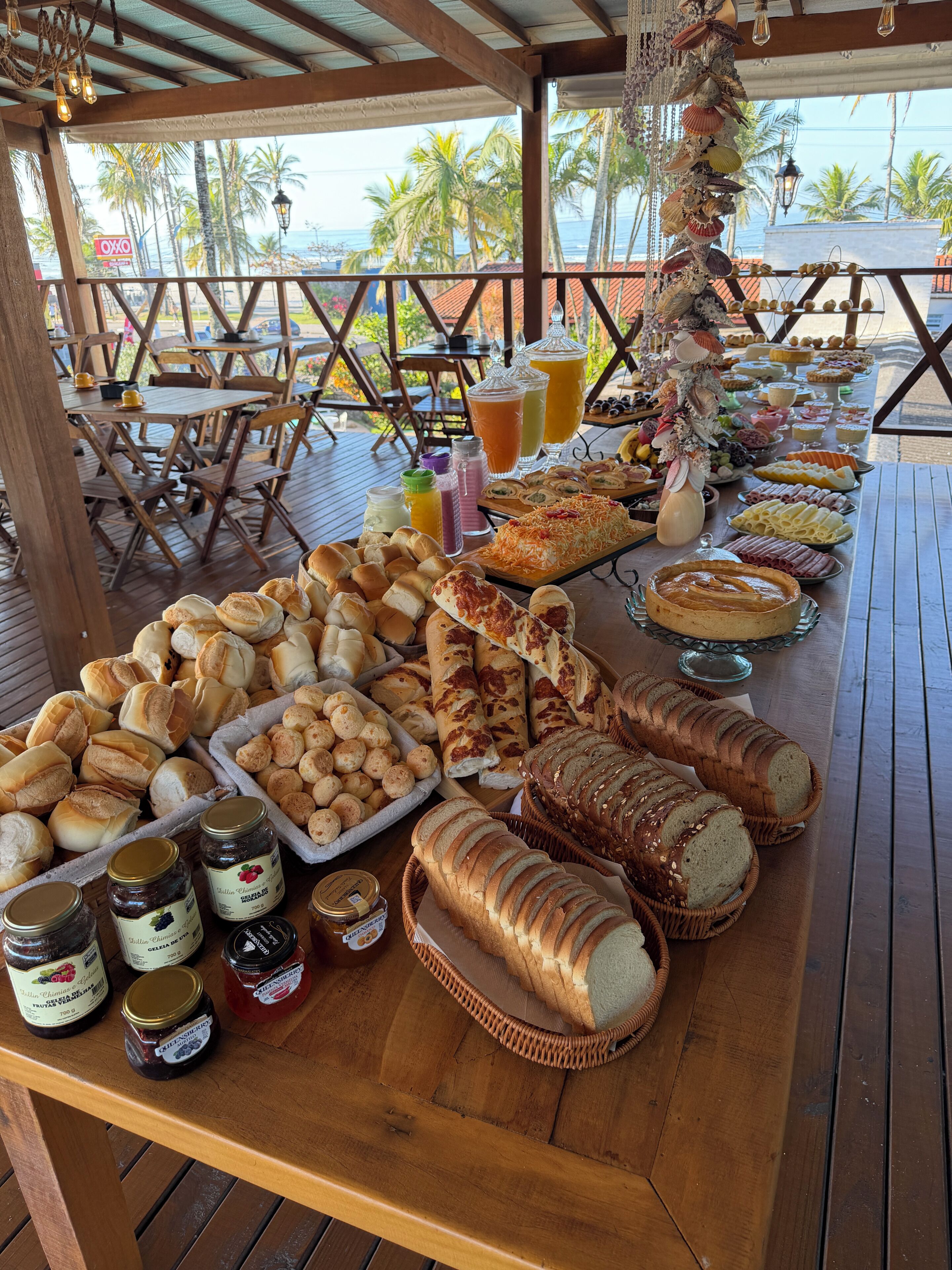 Mesa de buffet com diversos pães, doces e acompanhamentos.