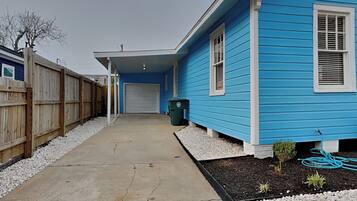 Uma casa residencial com fachada azul, calçada de concreto e cerca de madeira.