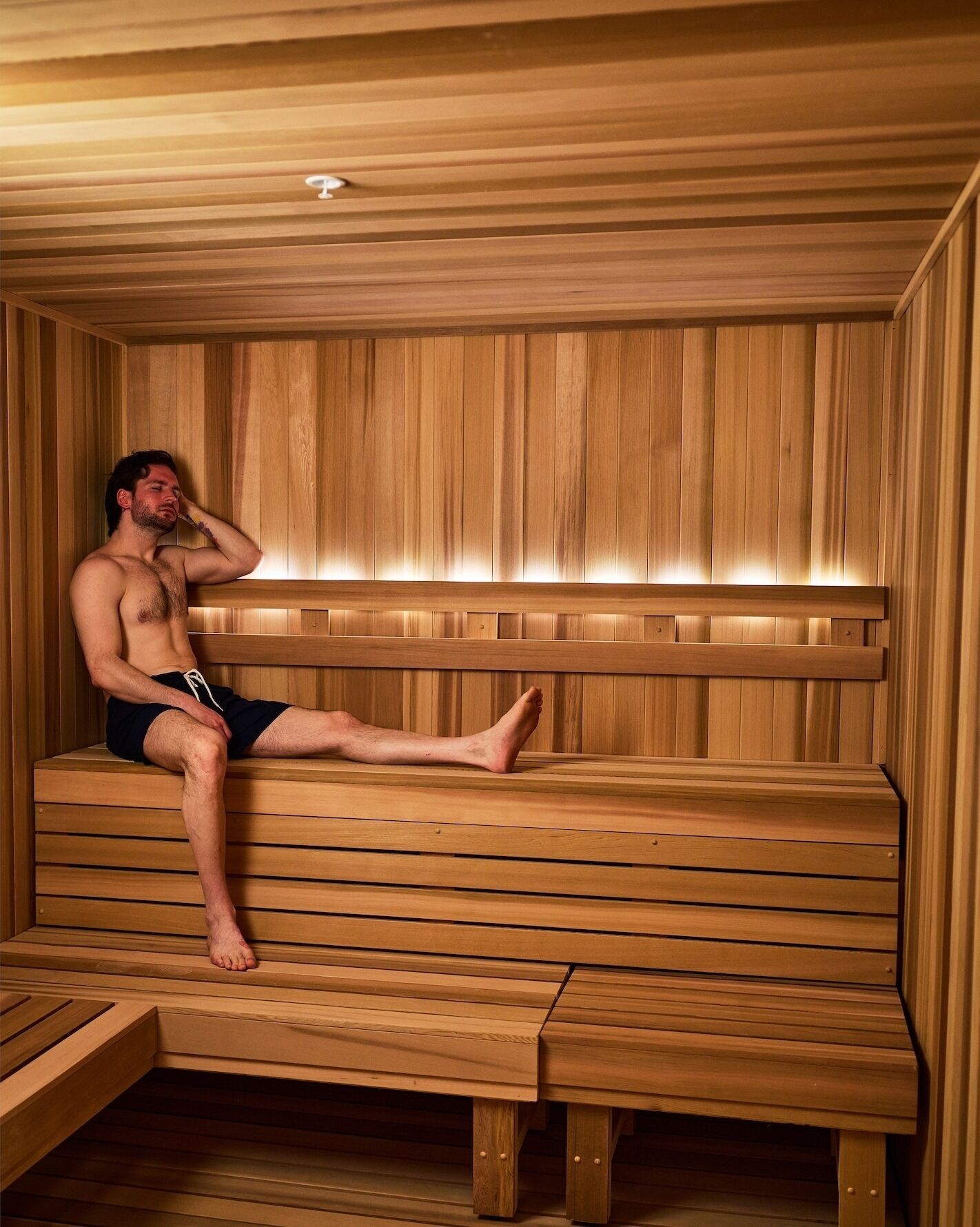Uma sauna com bancos de madeira e uma pessoa sentada em um deles.