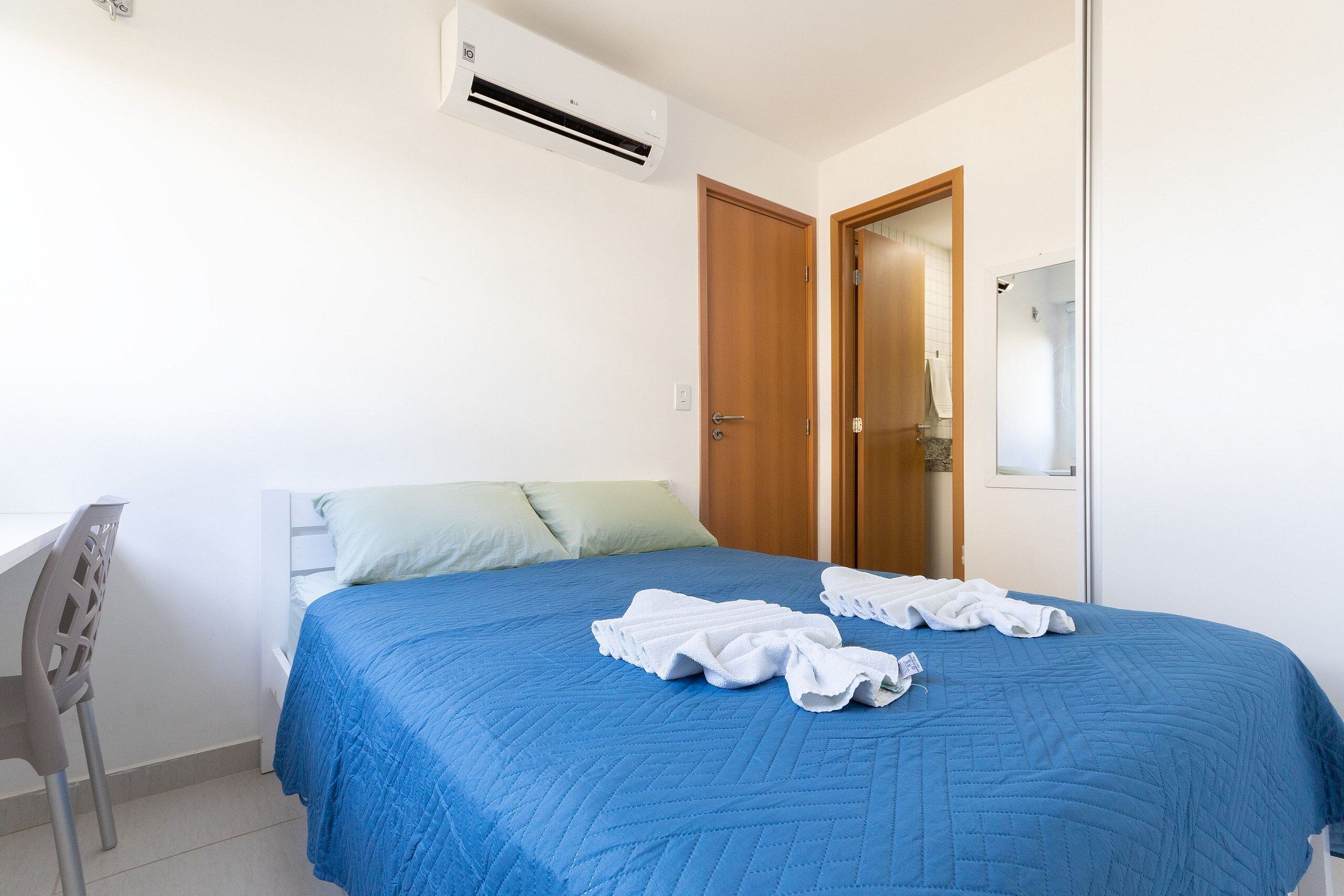 Quarto com cama, escrivaninha e ar condicionado.