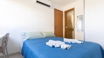 Quarto com cama, escrivaninha e ar condicionado.