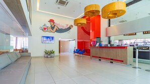 Um hall de hotel moderno com balcão de recepção, área de estar e um mural.